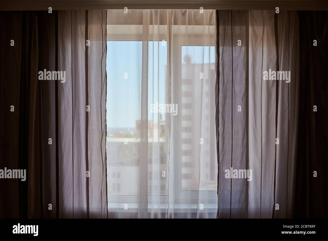 Windows with curtains in rental apartment. Cityscape view. Light window ...