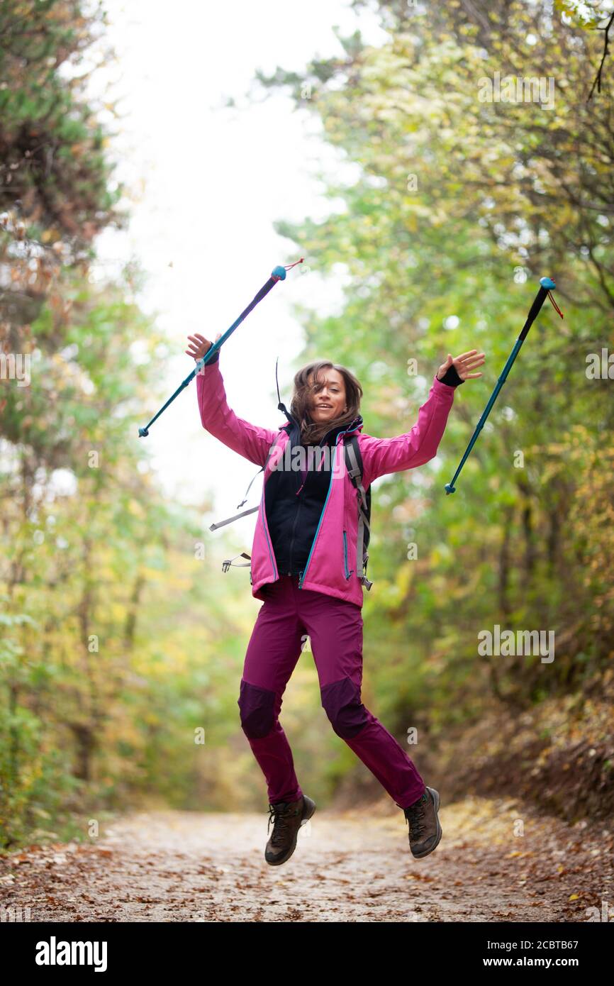 Hiker girl jumping on a trail in the mountains. Backpacker with hiking ...