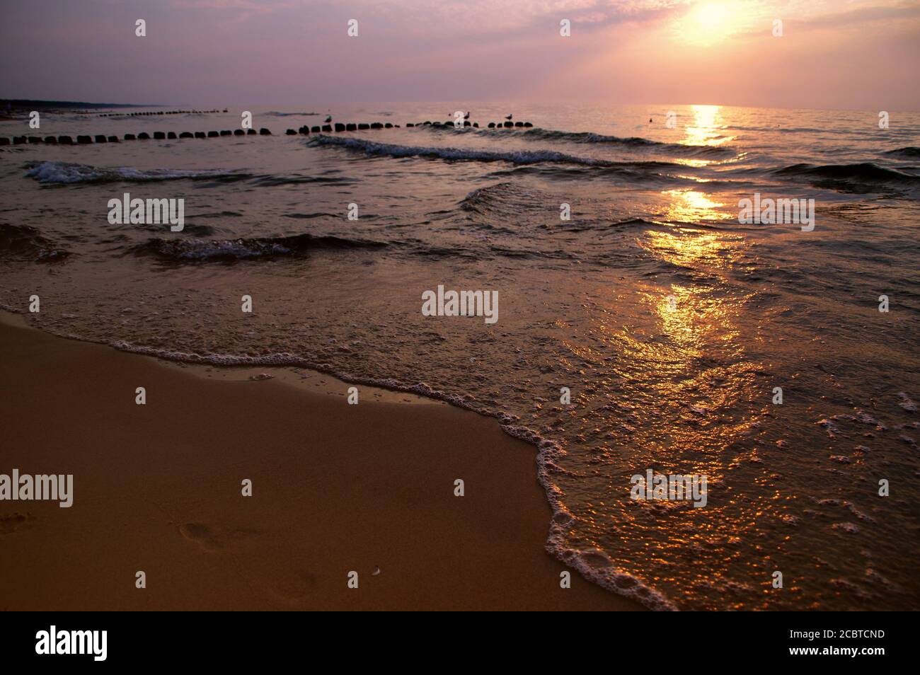 Sunset by the sea. Spectacular fiery red sun above the background waves ...