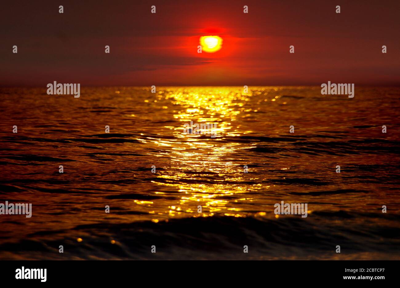 Sunset by the sea. Spectacular fiery red sun above the background waves ...
