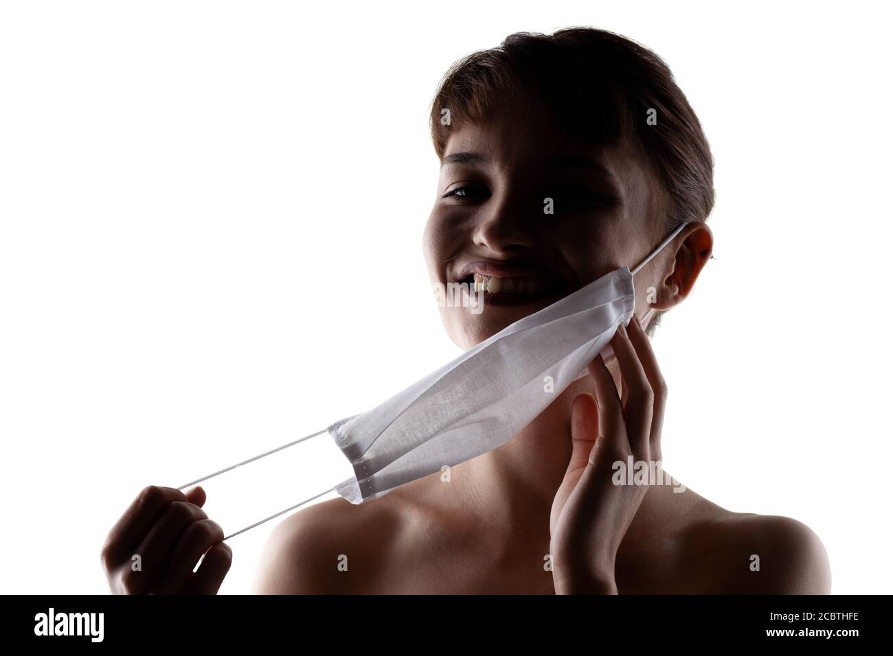 Half silhouette of a happy girl pulling off her medical face mask for ...