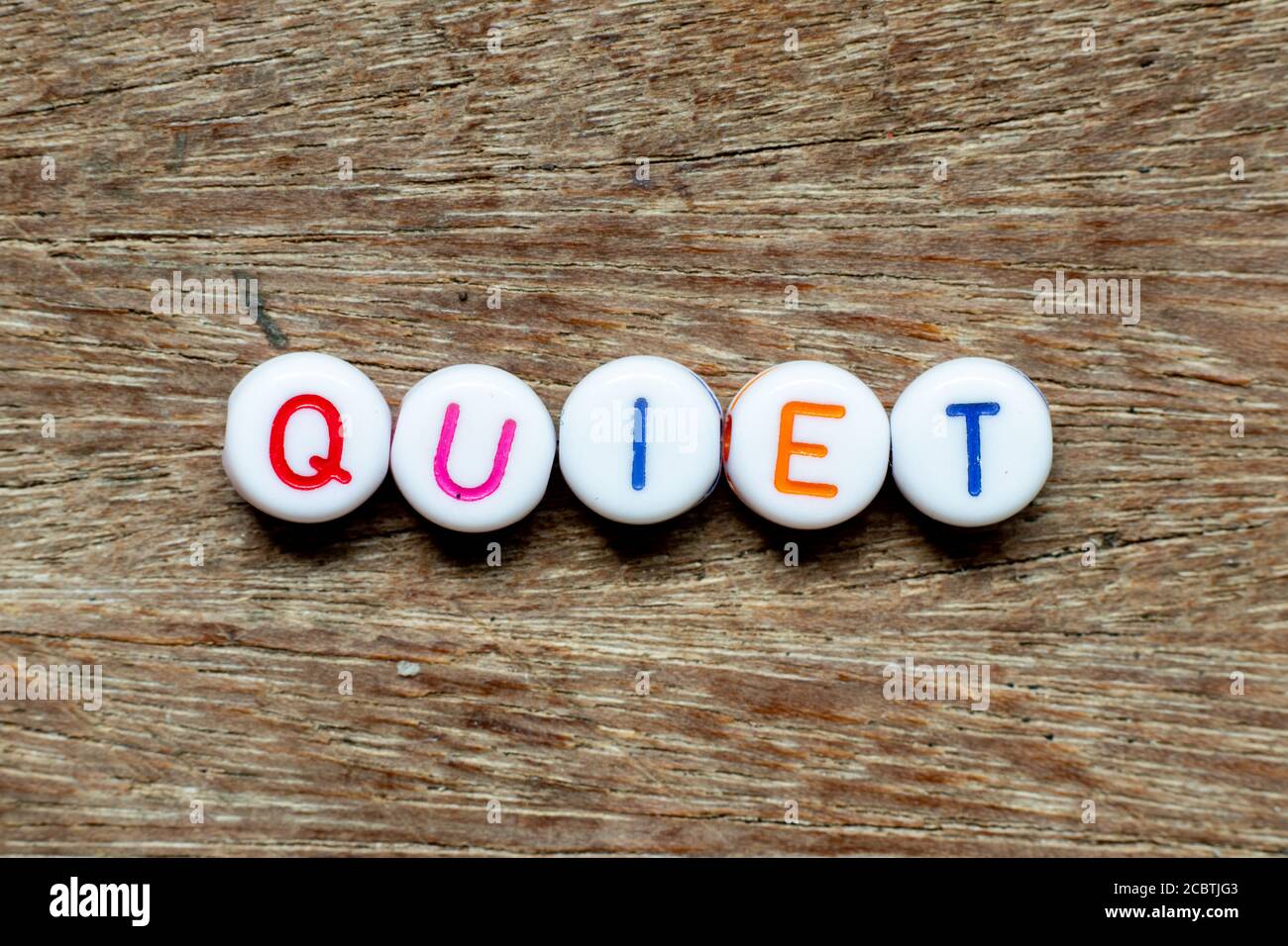 White bead with color letter in word quiet on wood background Stock ...
