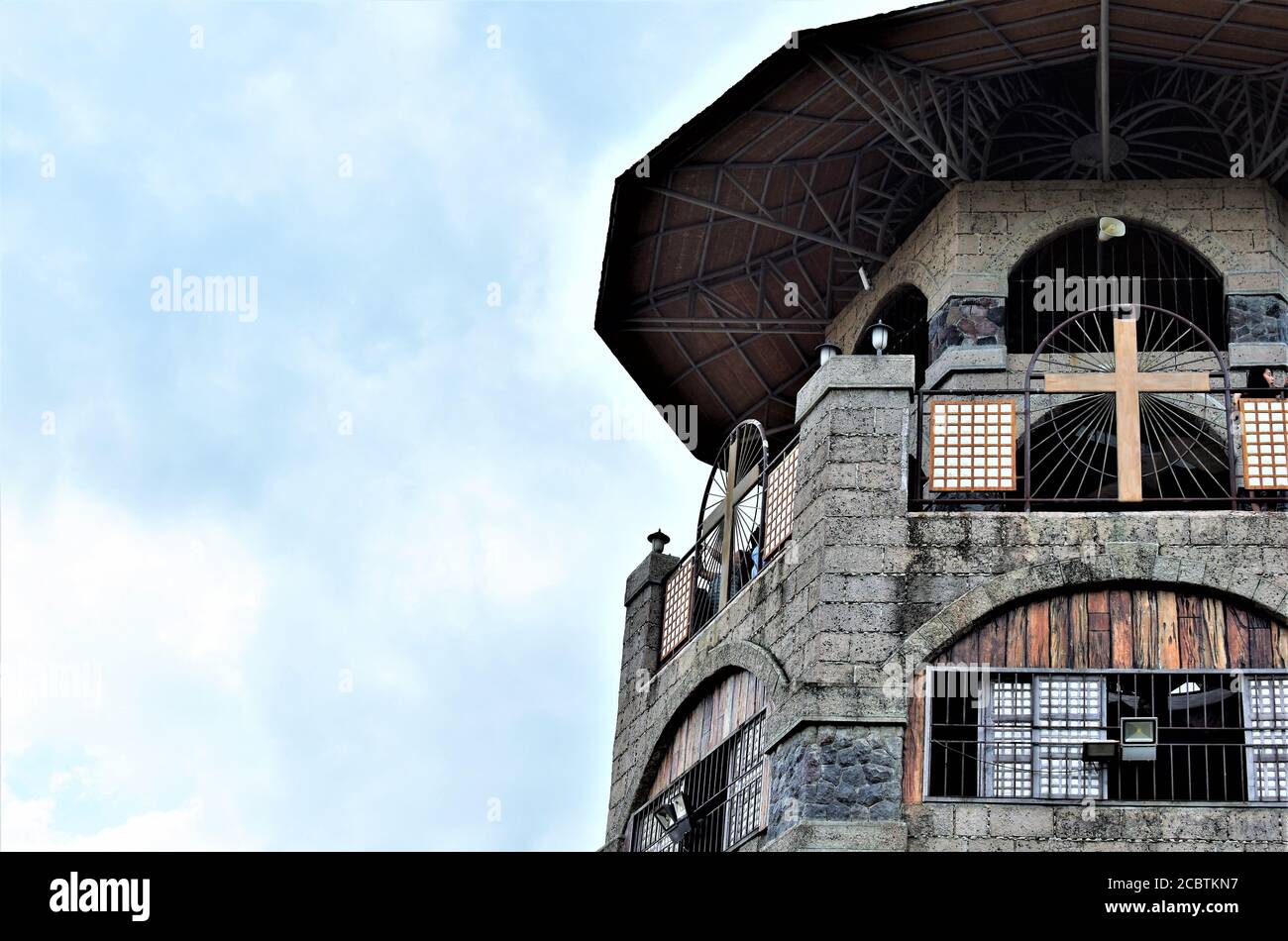 Façade of a stone church belfry with a sign of the cross at the top and ...