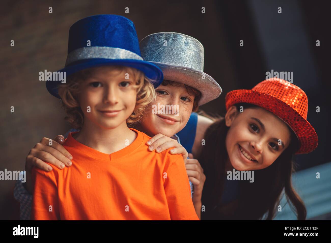 Three friends in party hats looking happy Stock Photo - Alamy