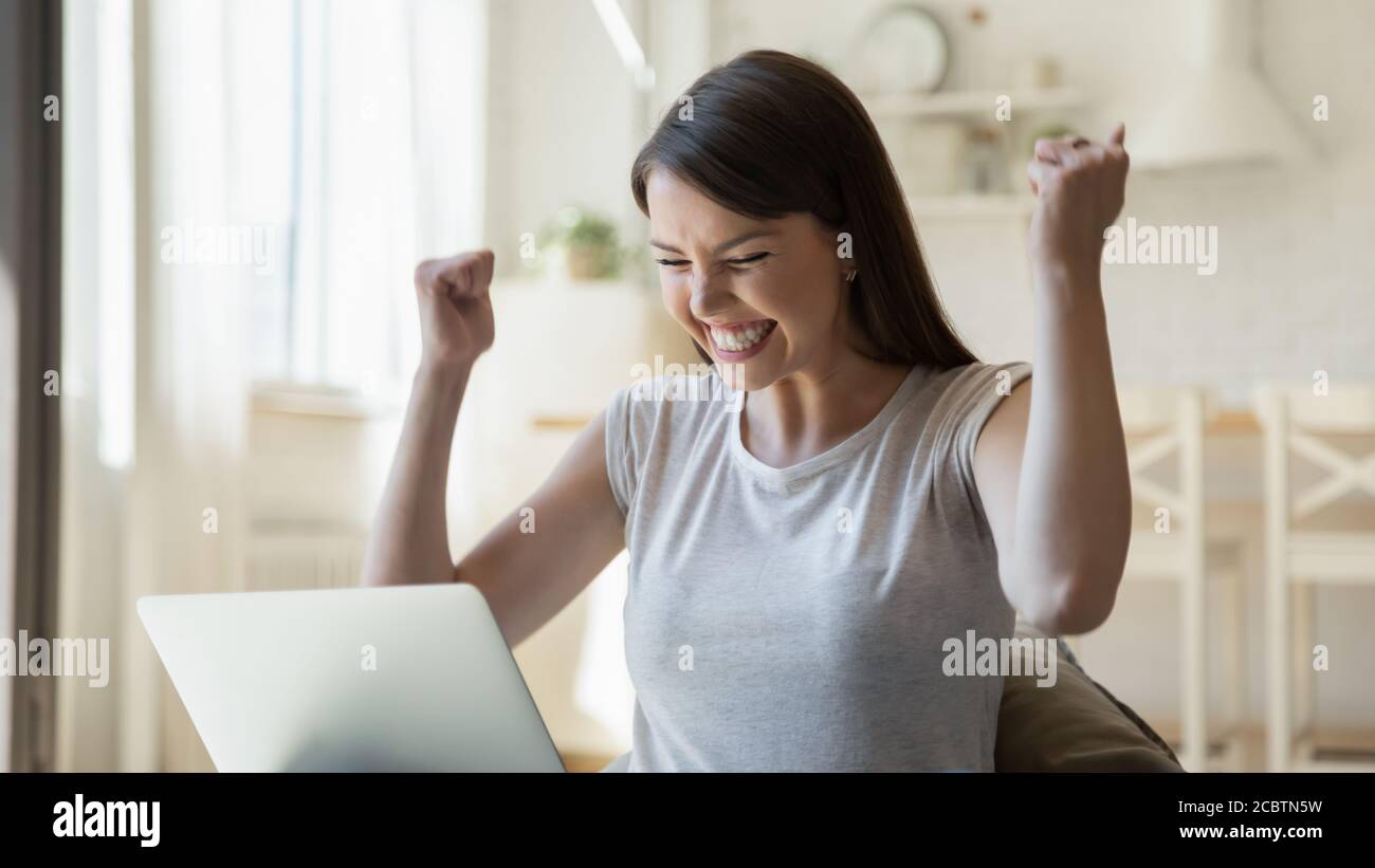 Excited young woman looking on screen of her laptop Stock Photo - Alamy