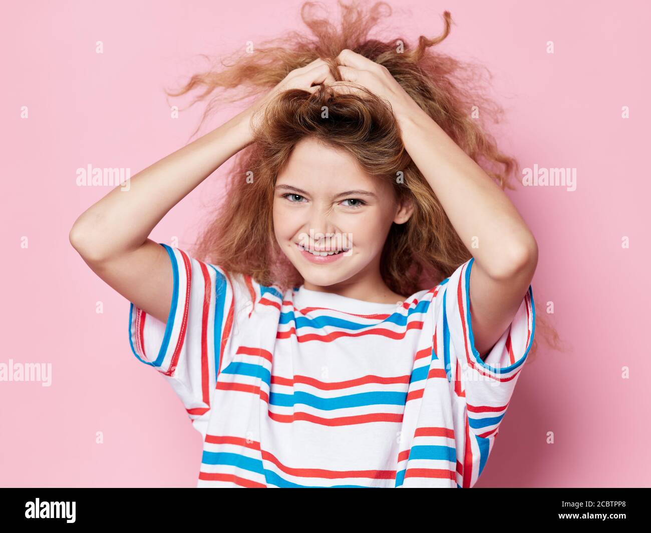 Girl with tousled hair holds hands on her head Stock Photo - Alamy