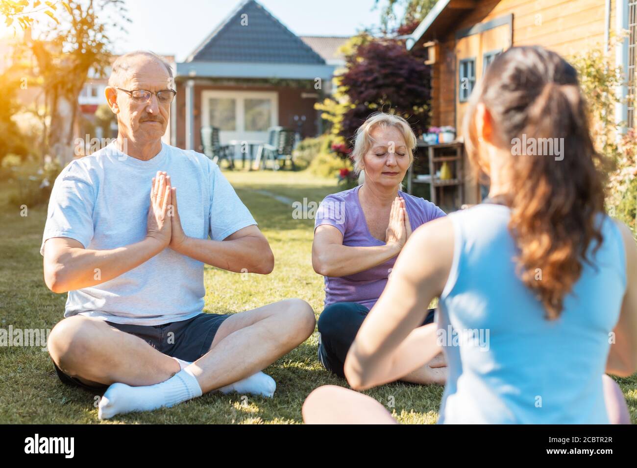 Group session of yoga outdoors, old people with trainer making ...