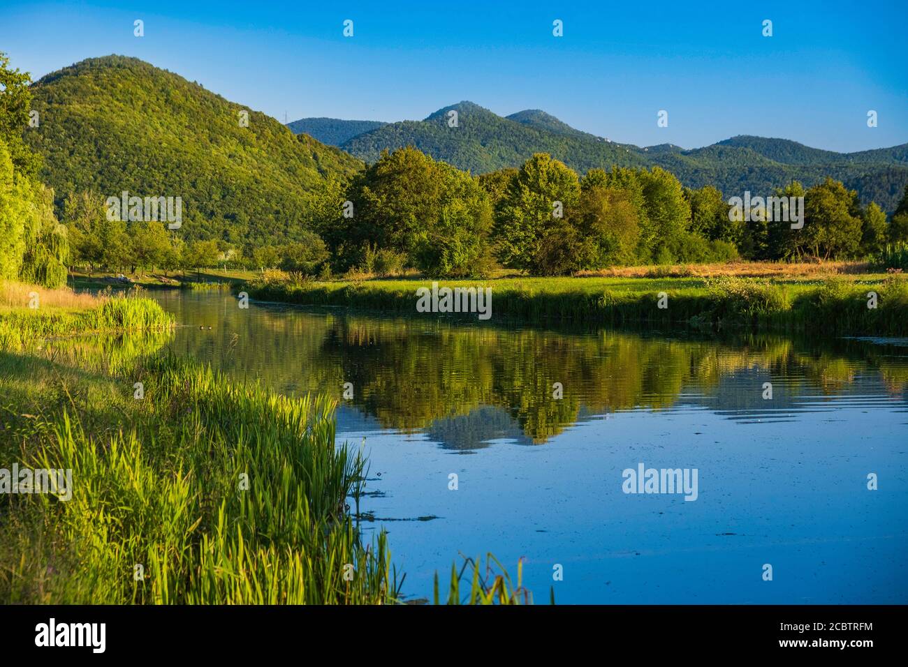 Gacka river flowing between green fields in Lika region of Croatia ...