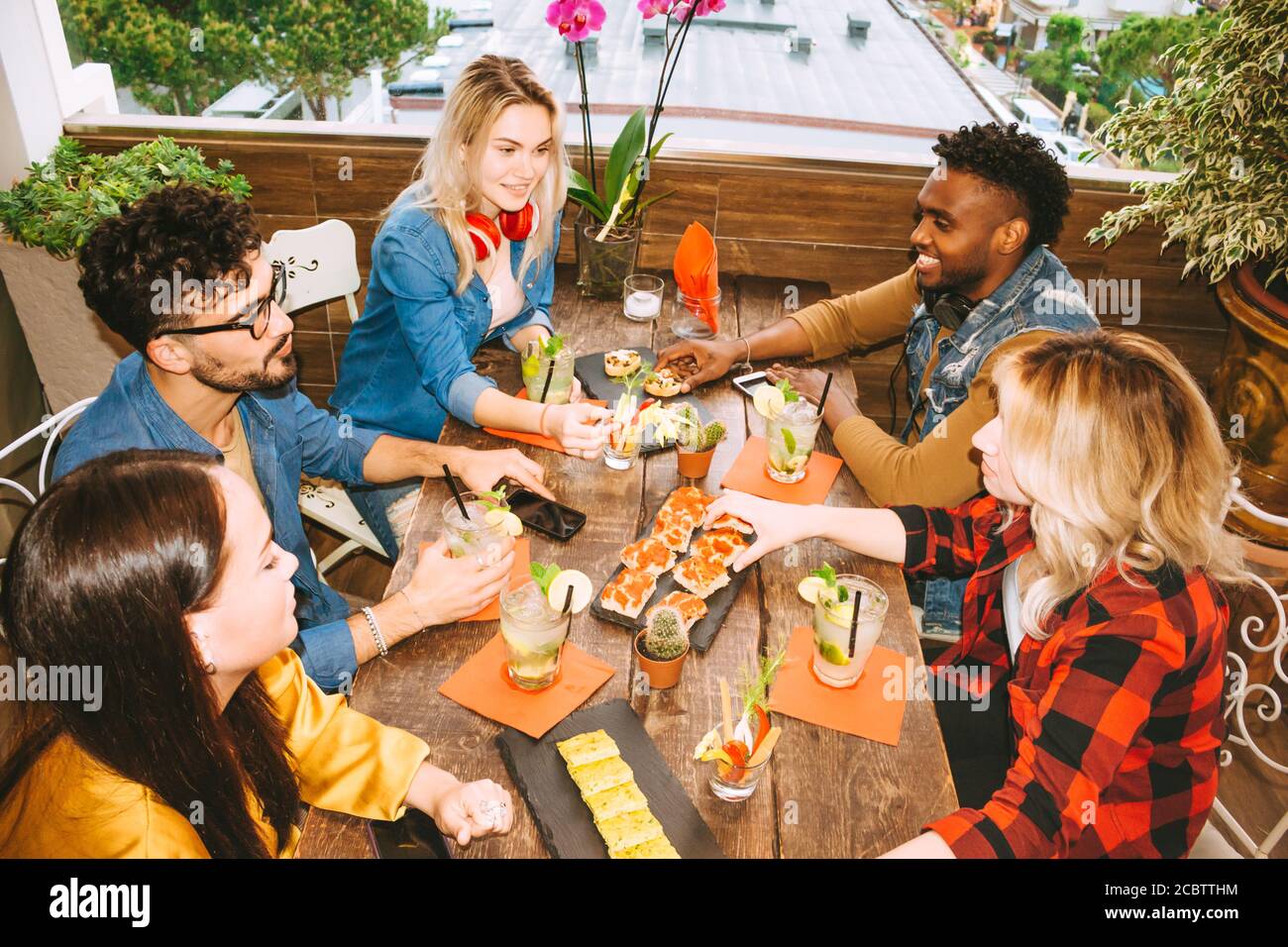 Multiracial group of young millennials friends talking and dining ...