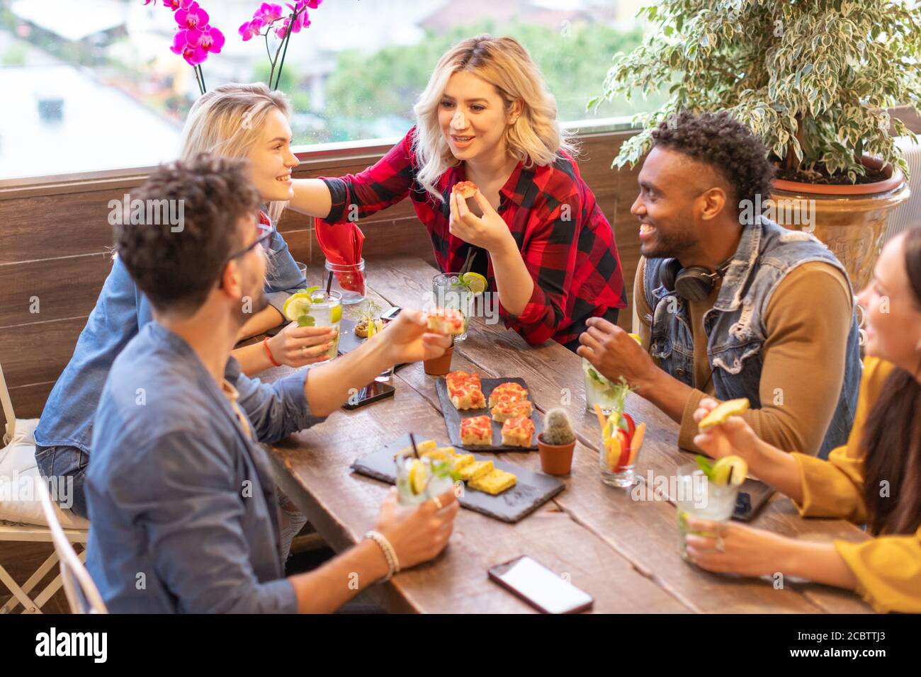 Multiracial group of young millennials friends talking and dining ...