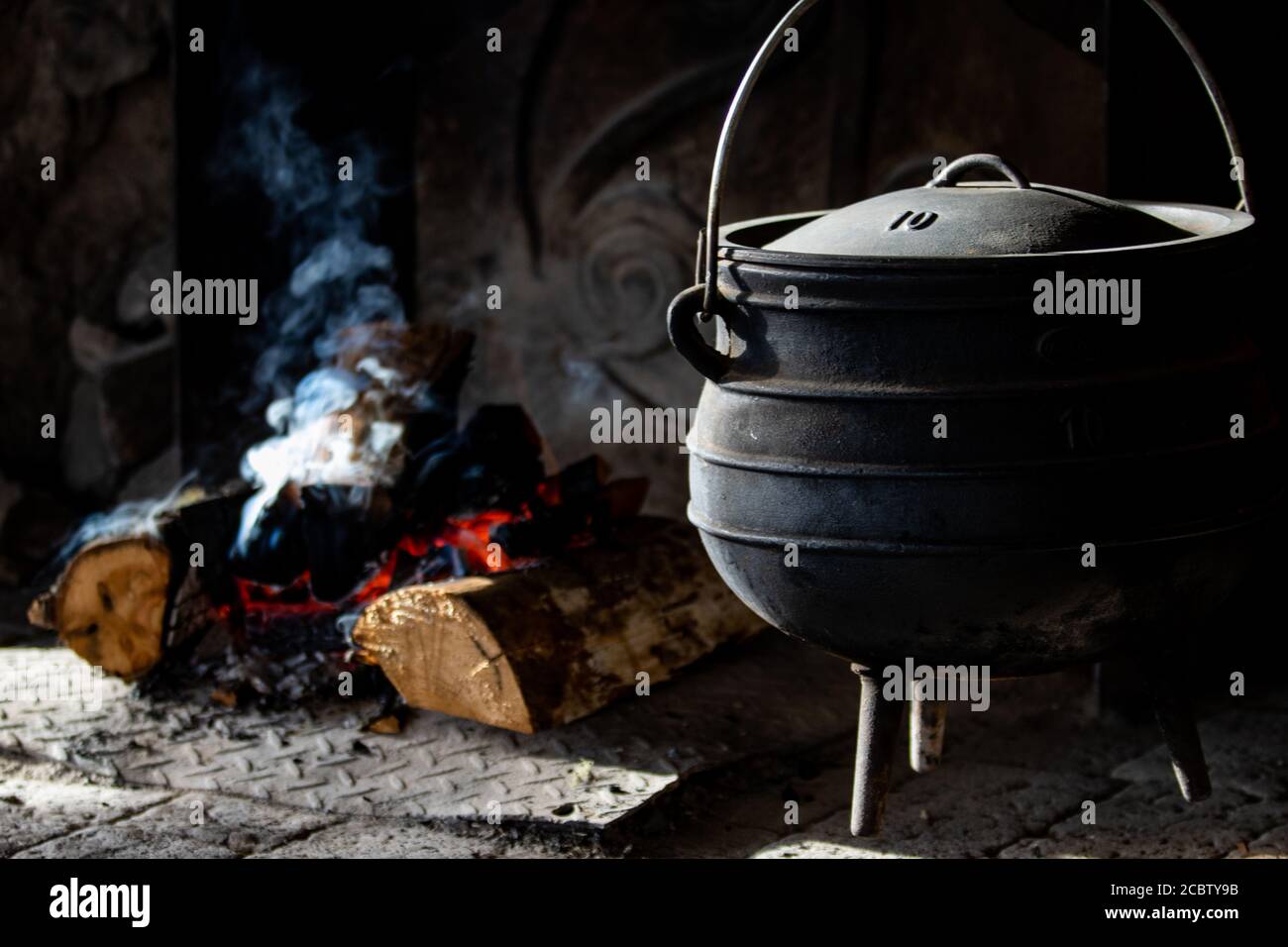 Traditional African three-legged cauldron on the burning logs ...