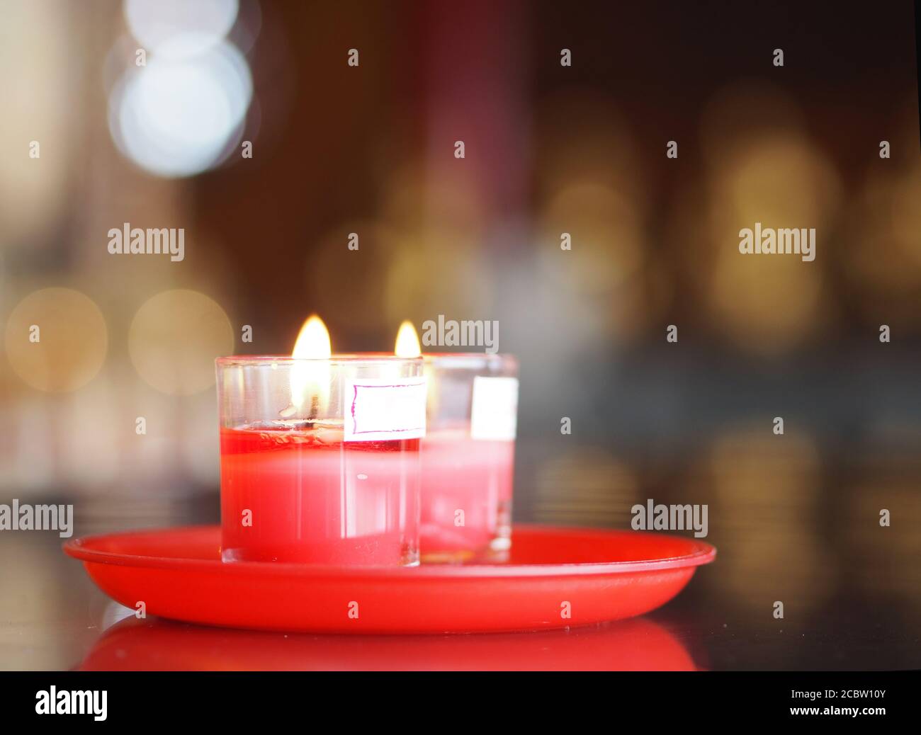 Red candles in clear glass lit on the candle holder at temple ...