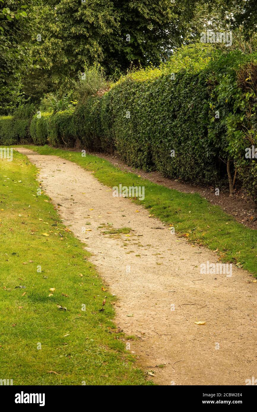 Footpath leading across to left with fresh green hedgerow on one side ...