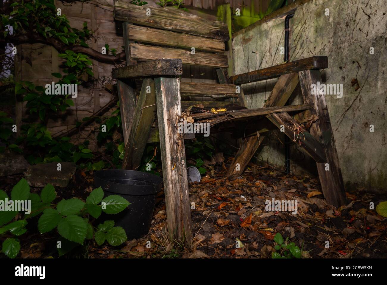 Decaying wooden garden chair abandoned in the forgotten corner of the ...