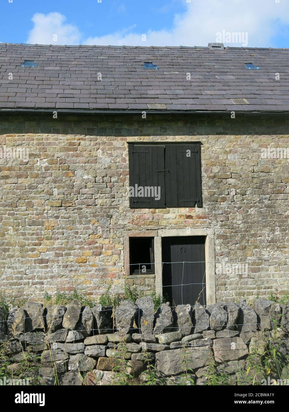 Close-up of a traditional stone farm building with wooden shutters ...