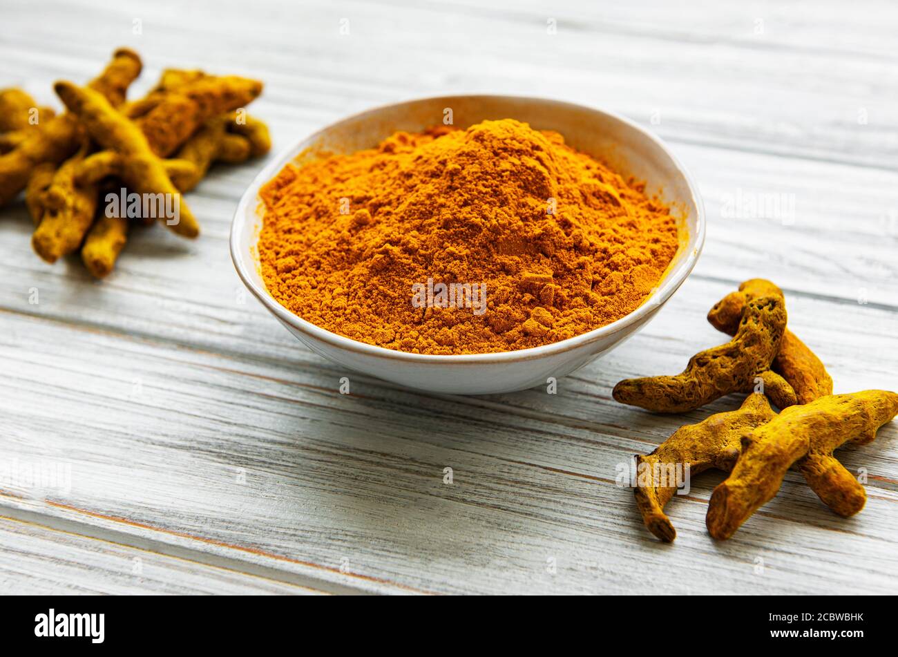 Yellow turmeric powder and dry roots on wooden background Stock Photo ...