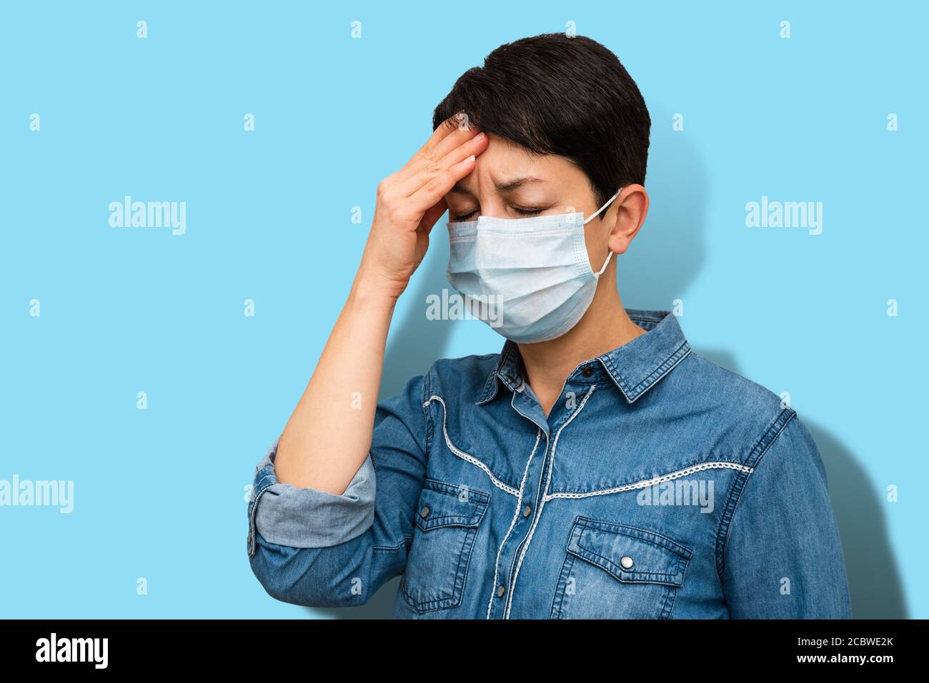 Woman feeling strong headache holding head on light blue background ...
