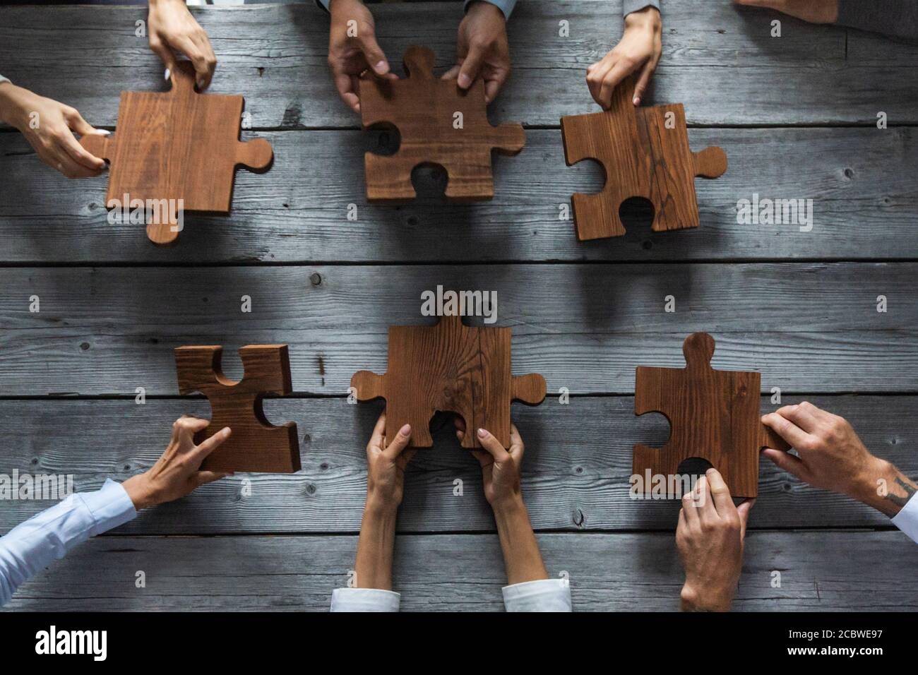 Business people team sitting around meeting table and assembling wooden ...