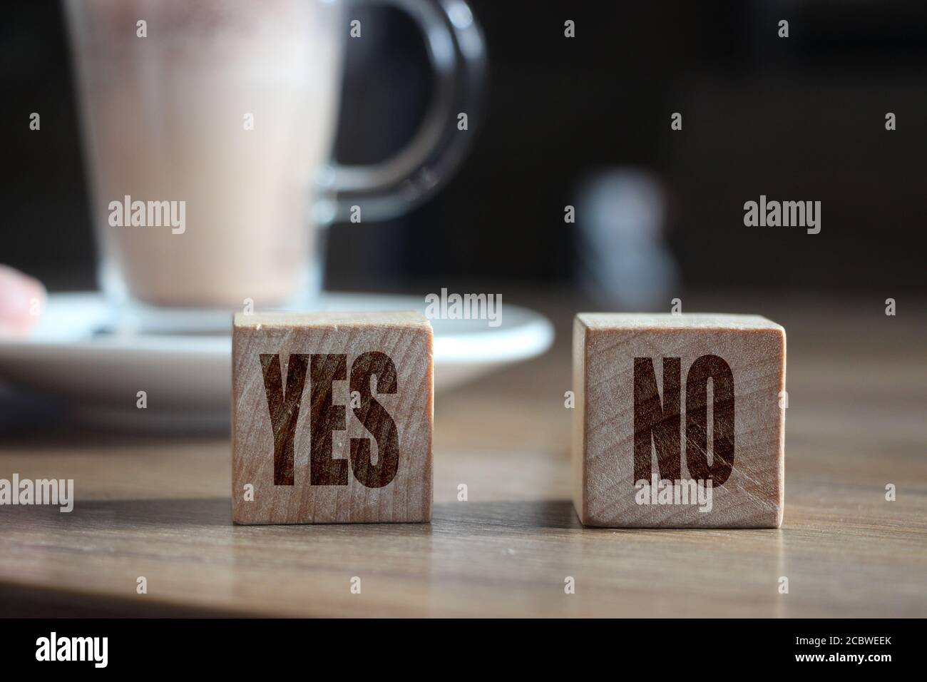 Yes versus no wooden cubes in front of cacao cup on table. Business ...