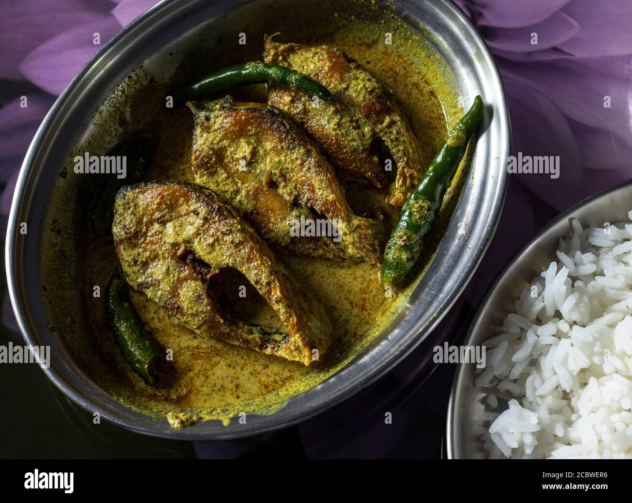 high angle view of hilsa fish curry with mustard paste and green chilli ...
