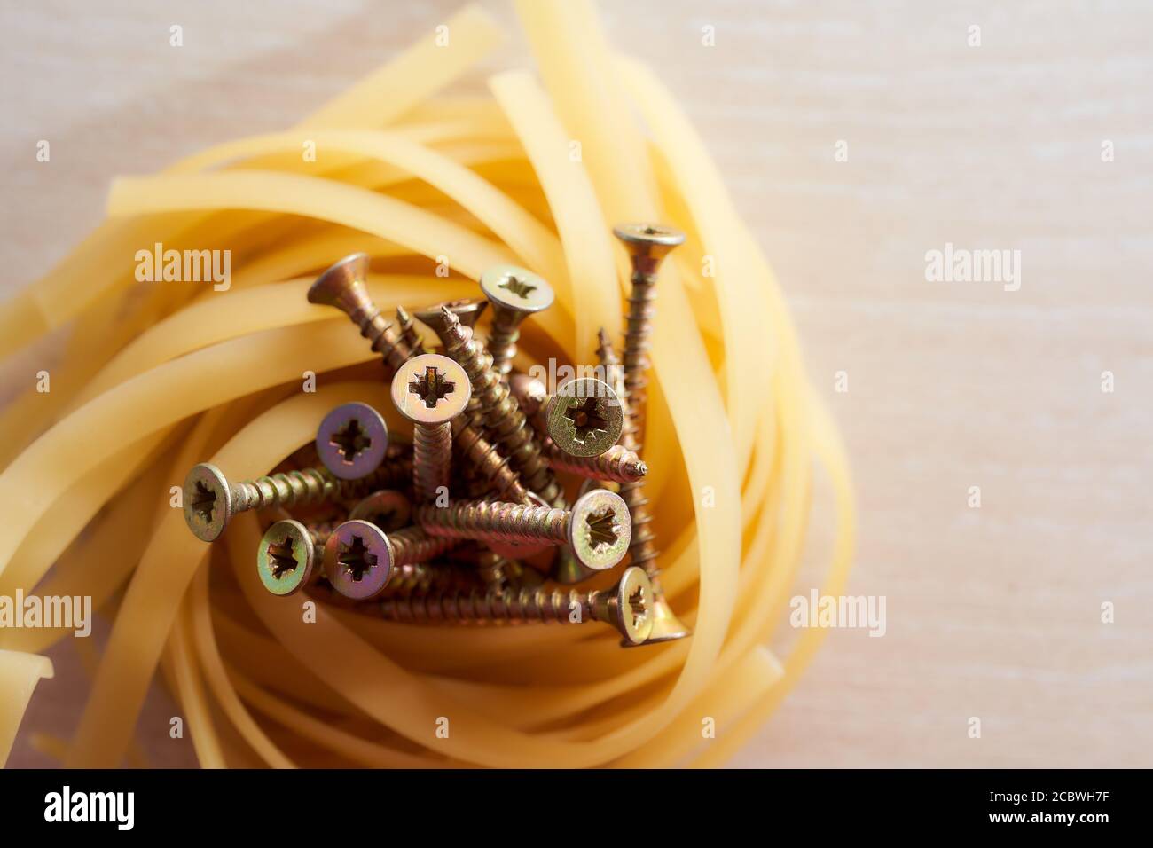 The screws lie in the nest of spaghetti light background Stock Photo ...