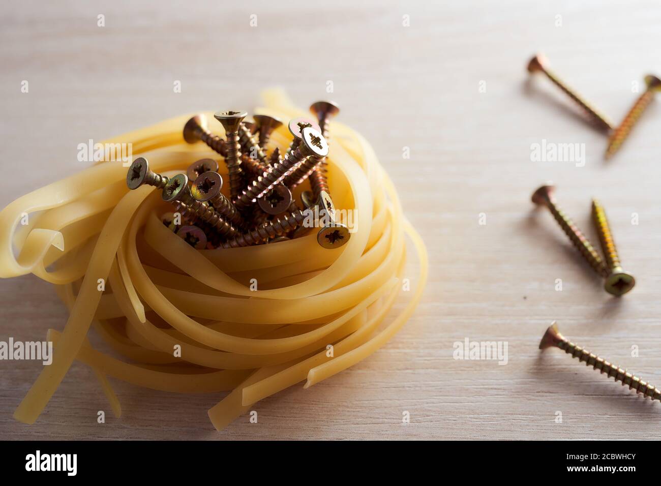 The screws lie in the nest of spaghetti light background Stock Photo ...