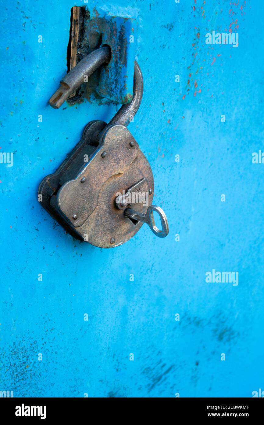 Old rusty lock with a key on a blue background Stock Photo - Alamy