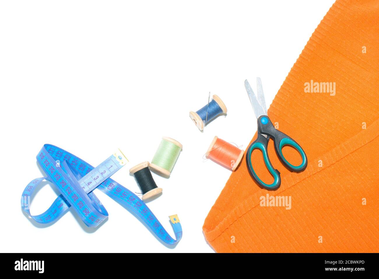 Coil with thread, scissors and ruler on a piece with a bright cloth, on ...