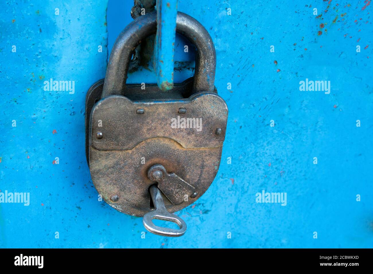 Old rusty lock with a key on a blue background Stock Photo - Alamy