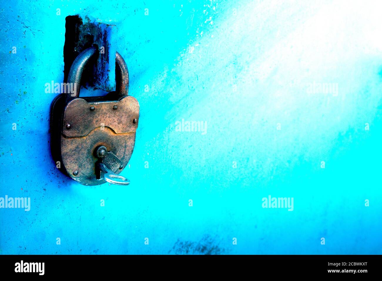 Old rusty lock with a key on a blue background Stock Photo - Alamy
