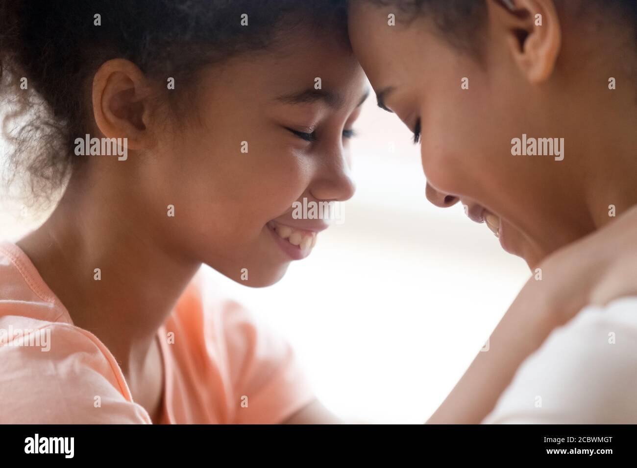 Close up of hugging african mother and daughter touching foreheads ...