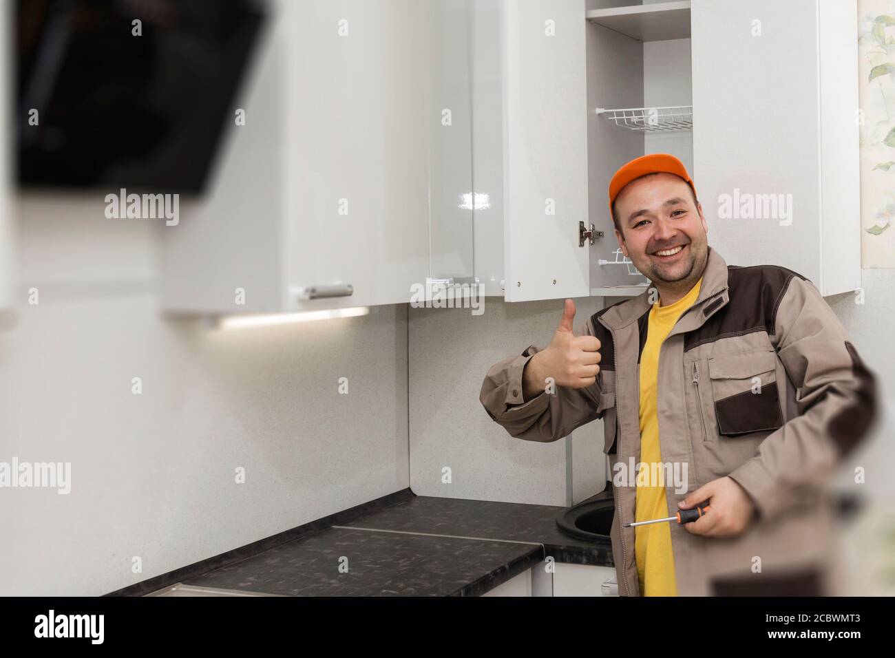 Happy worker. Assembly of kitchen furniture Stock Photo - Alamy