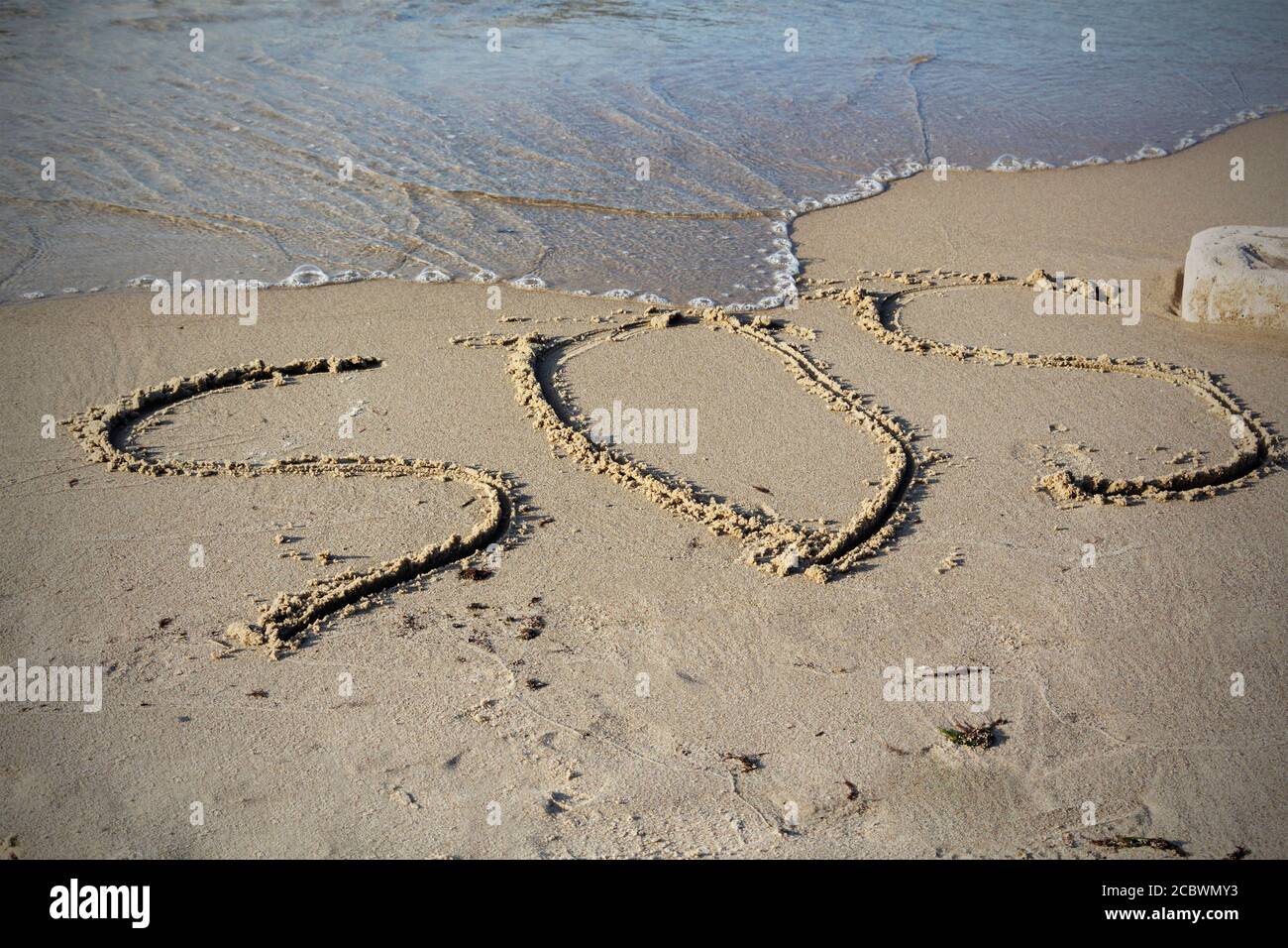 SOS - word drawn on the sand beach with the soft wave Stock Photo - Alamy
