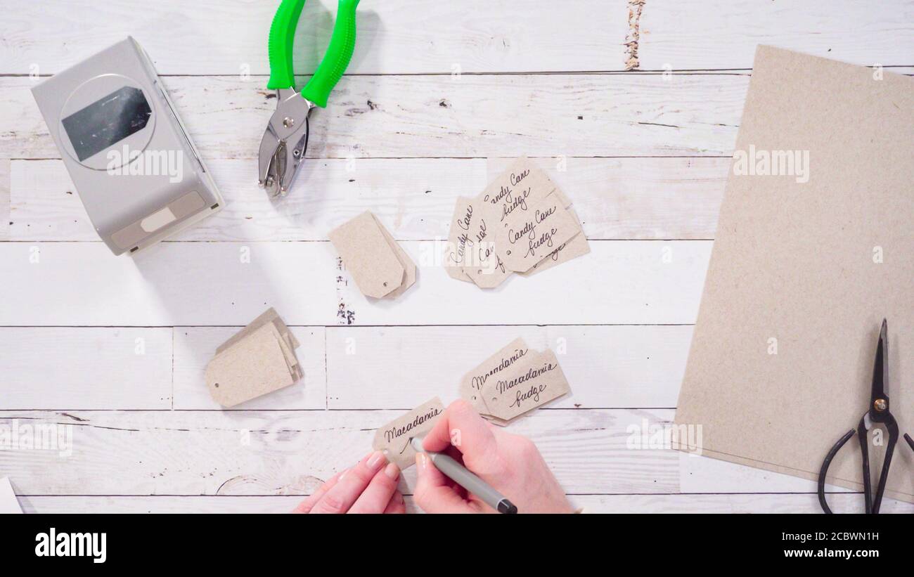 Flat lay. Step by step. Labeling brown paper gift tags with a black ...