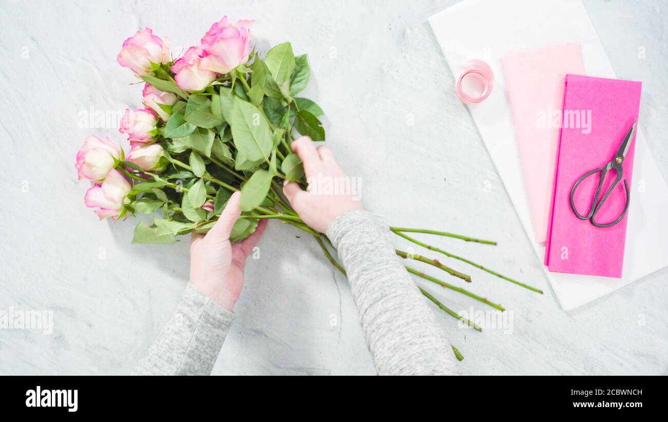 Flat lay. Step by step. Florist arranging a bouquet from pink roses ...