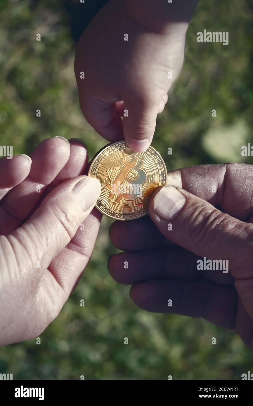 Hands of different people holding a gold coin bitcoin. Blurred ...