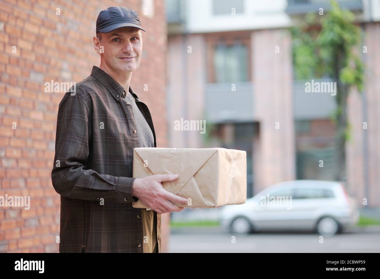 Delivery man with a box outdoors Stock Photo - Alamy