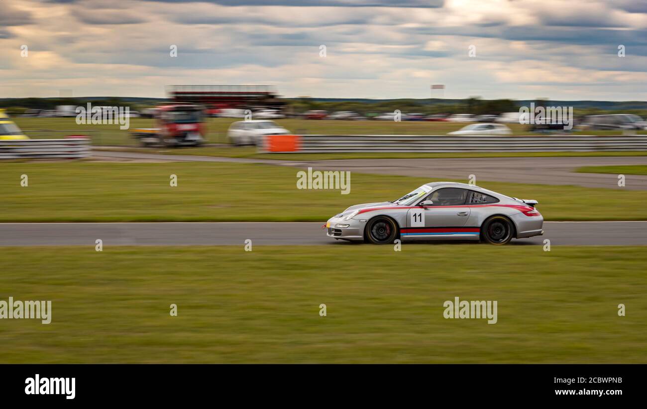 A panning shot of a silver racing car as it circuits a track Stock ...