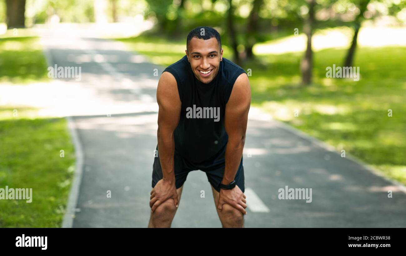 Smiling black jogger resting after marathon run at sunny park Stock ...