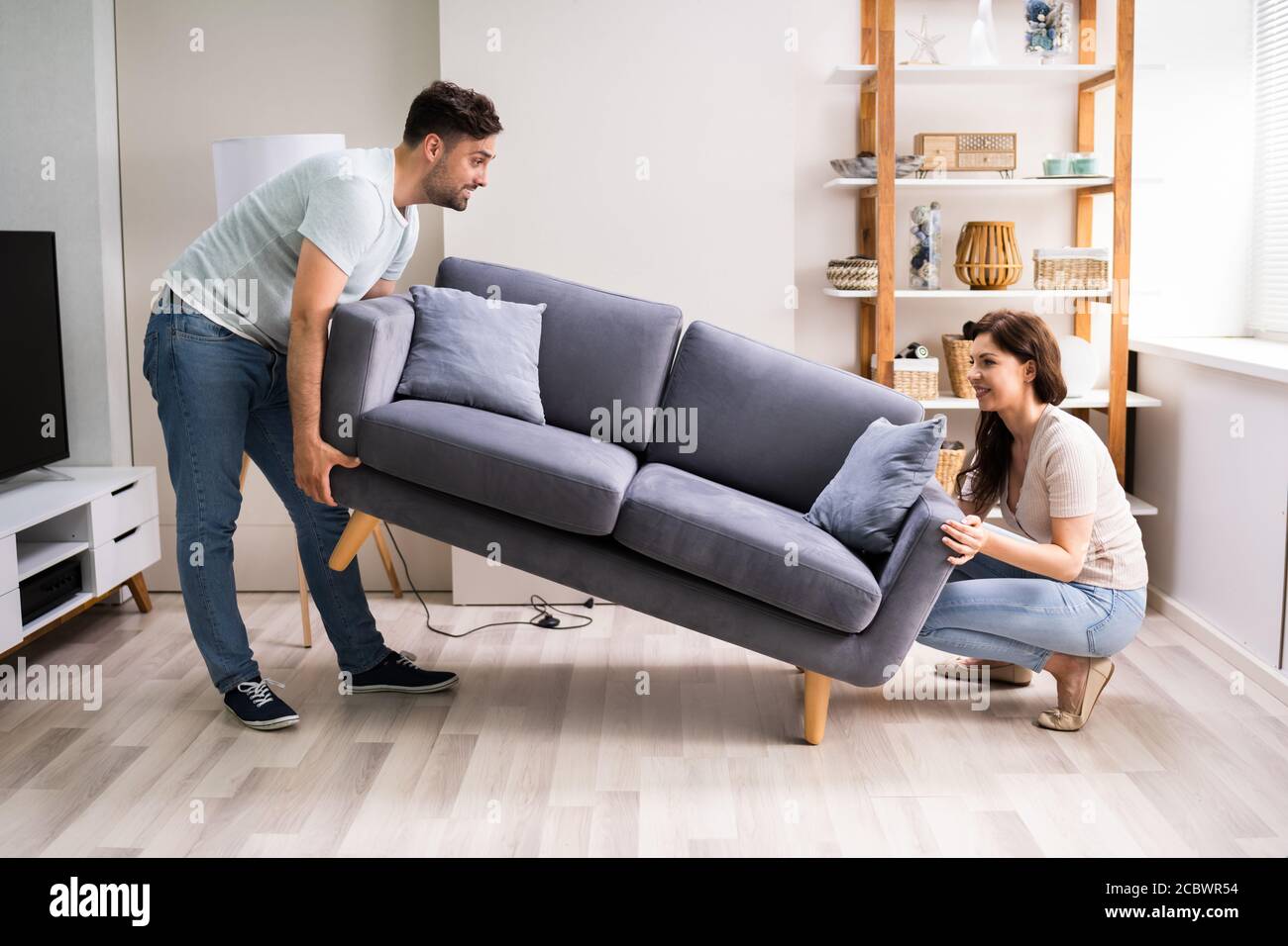 Couple Moving And Carrying Sofa Furniture Or Couch Stock Photo - Alamy