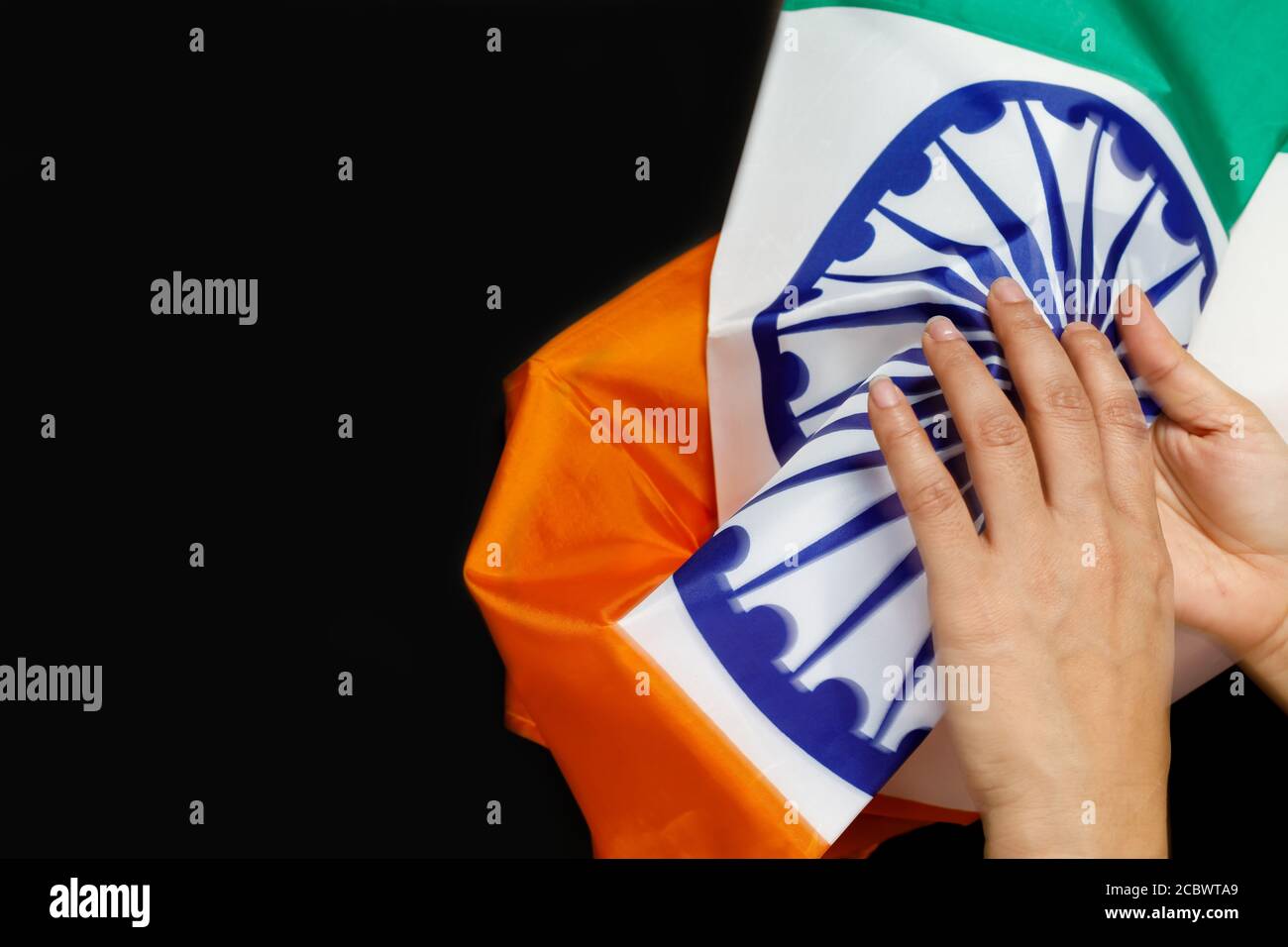 Top view of human hands holding a National Flag of India on black ...