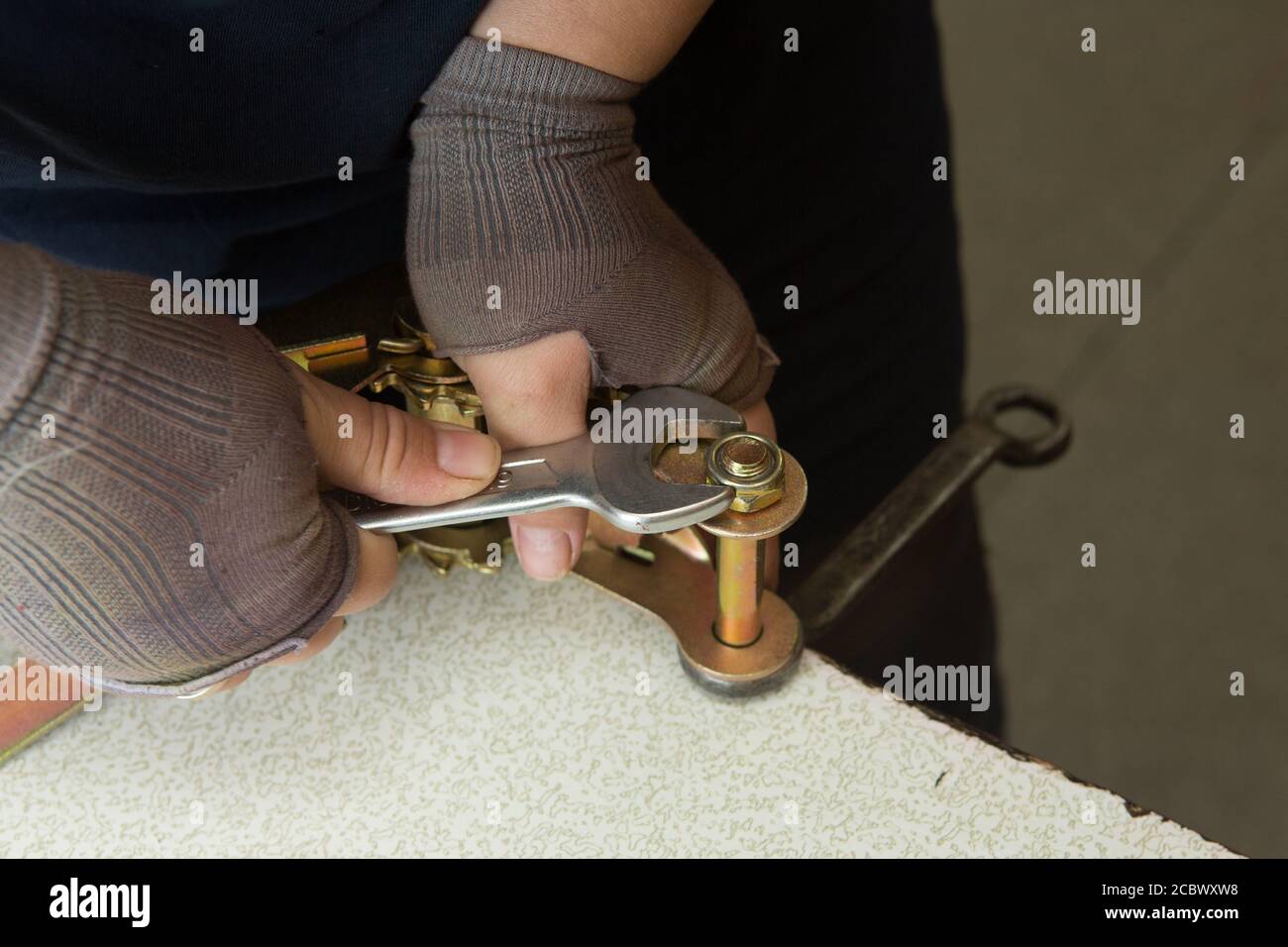 Woman mechanic working in metal workshop using clamps, screws, and ...