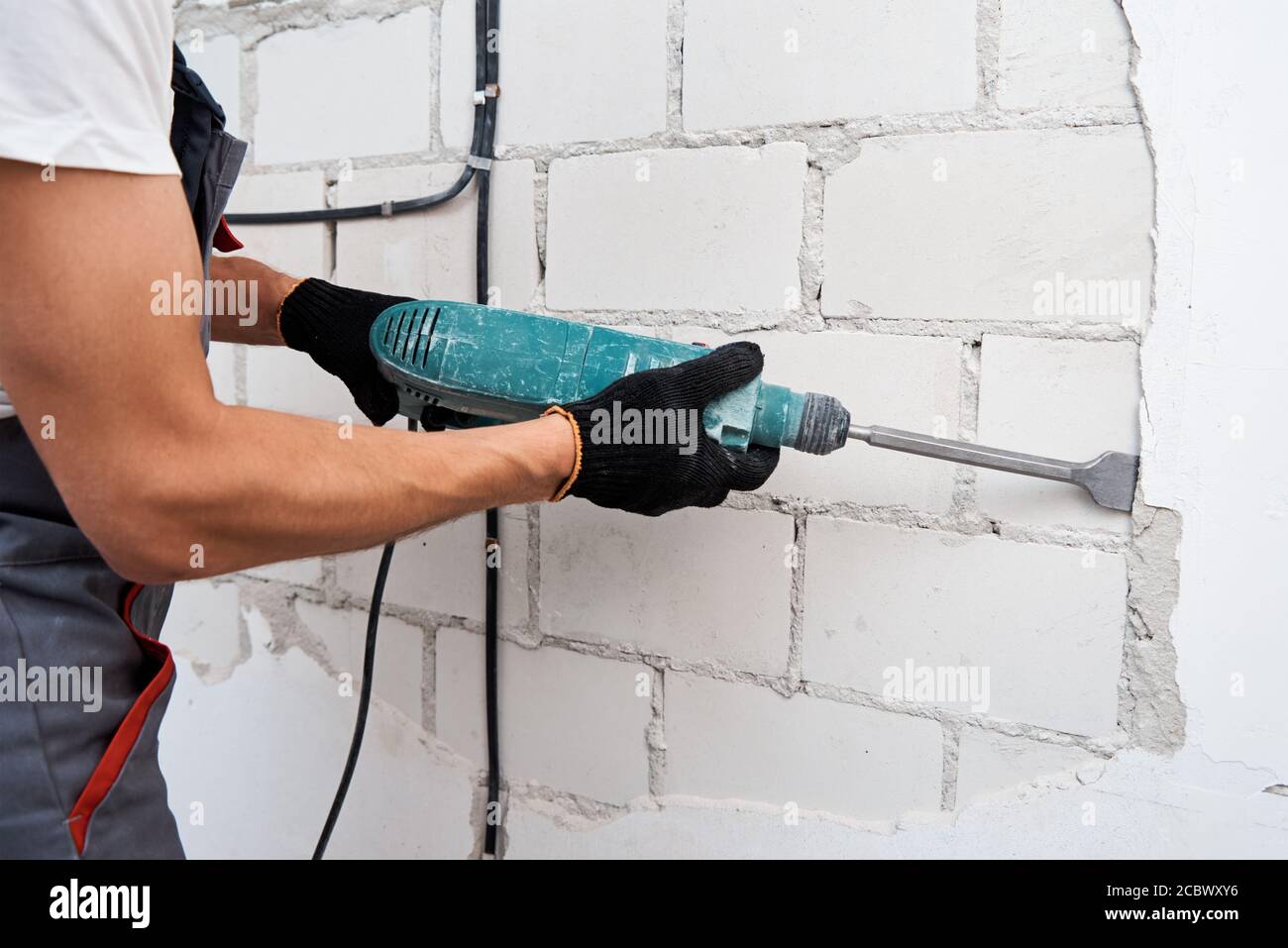 Renovation concept. Man with demolition hammer remove stucco from wall ...