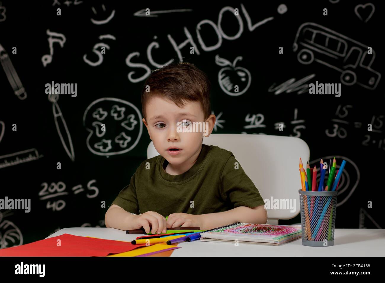 Cute child boy doing homework. Clever kid drawing at desk. Schoolboy ...