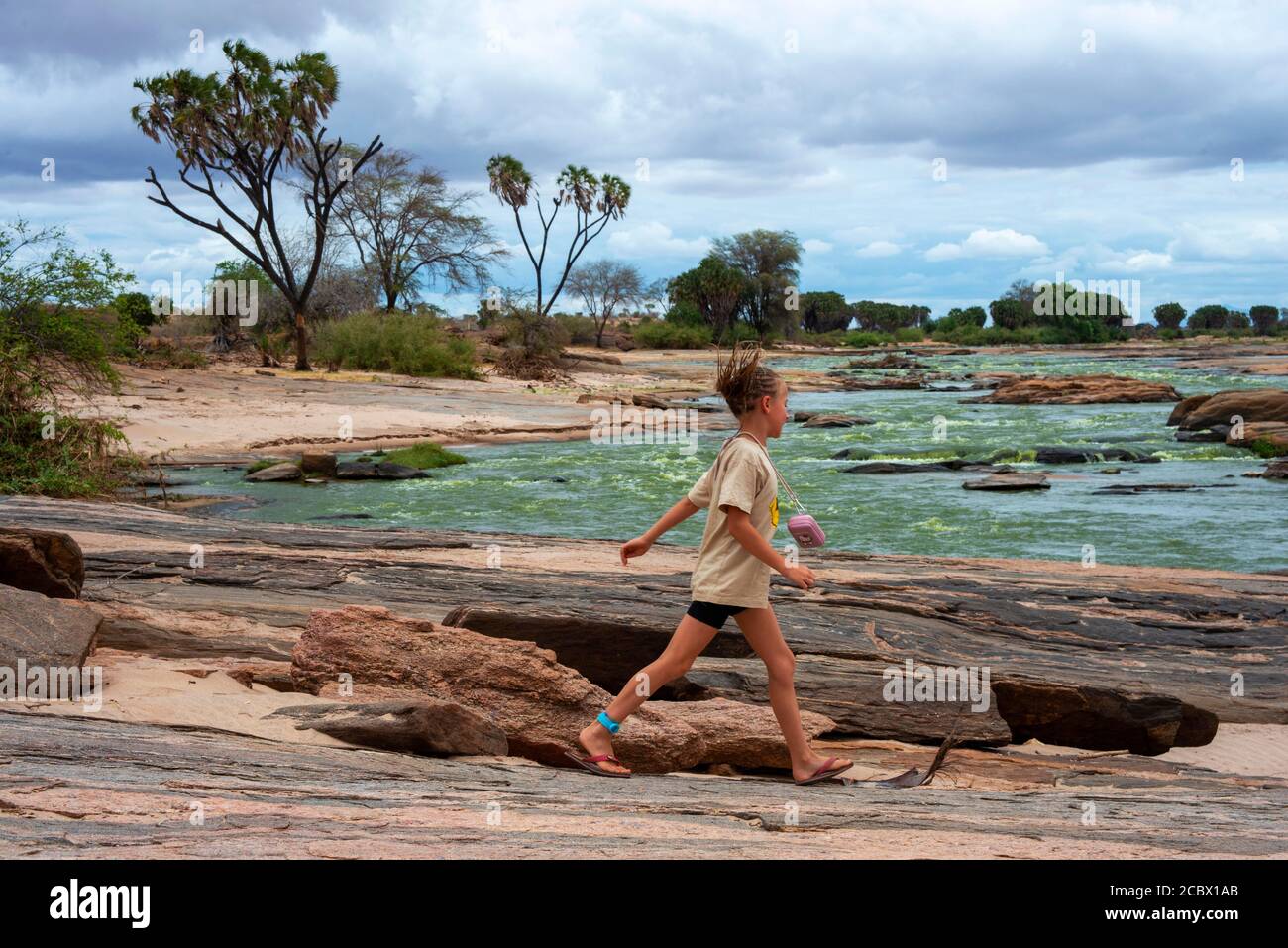 Tourist girl in the Voi river in front of Taita Hills, Tsavo East ...