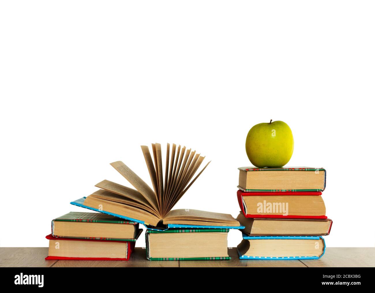 Open textbook, pile of books in colorful covers and green apple on ...