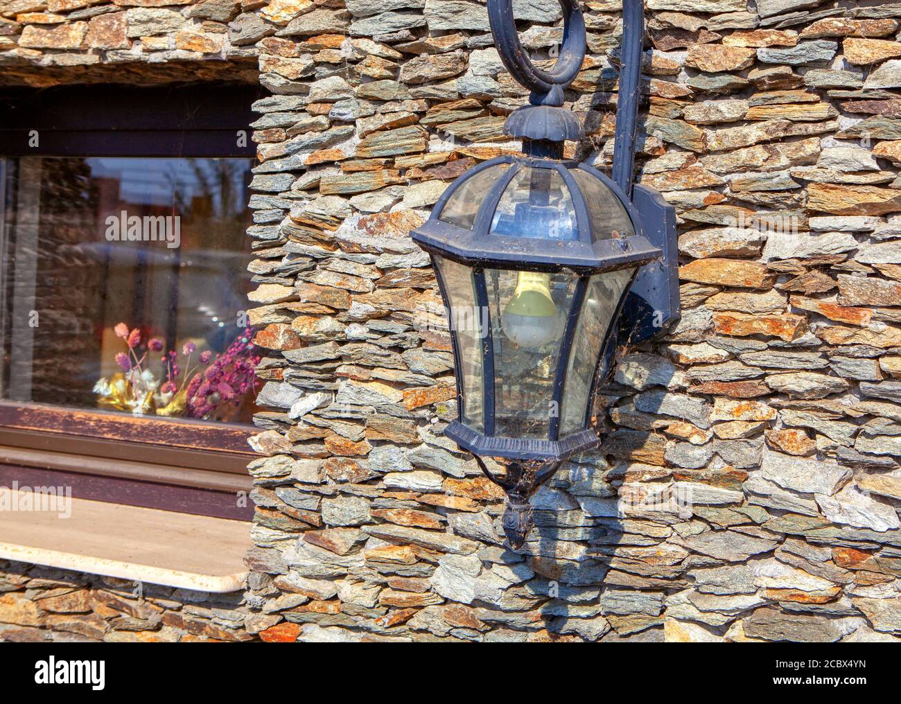 Plaster with stones wall with lamp in medieval style Stock Photo - Alamy