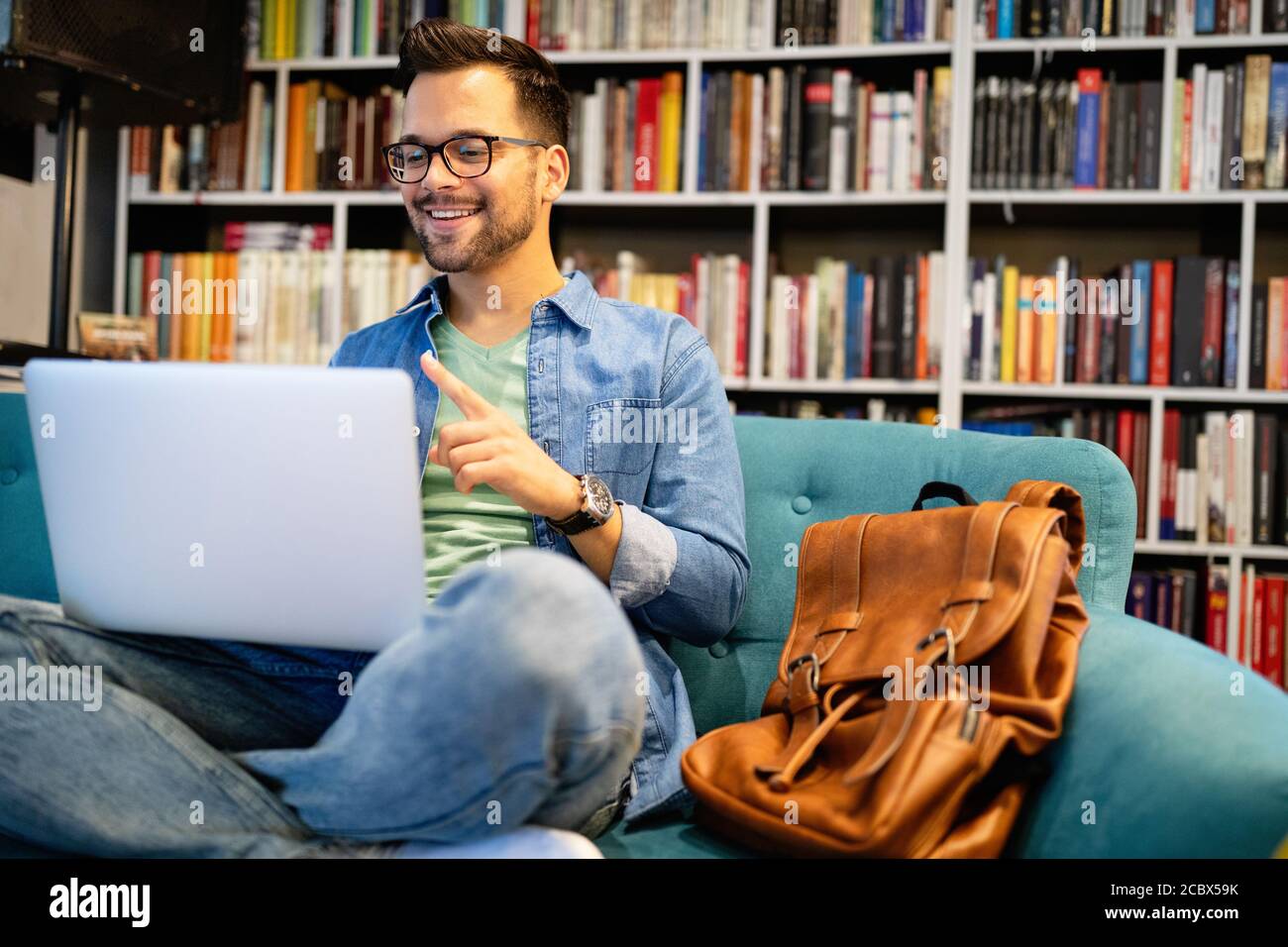 Smiling male student working and studying in a library Stock Photo - Alamy