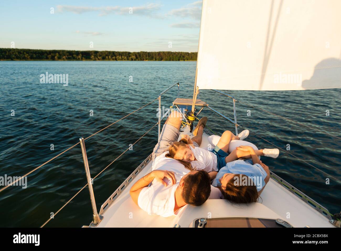 Family Lying On Yacht Deck Relaxing On Sailboat Ride Stock Photo - Alamy
