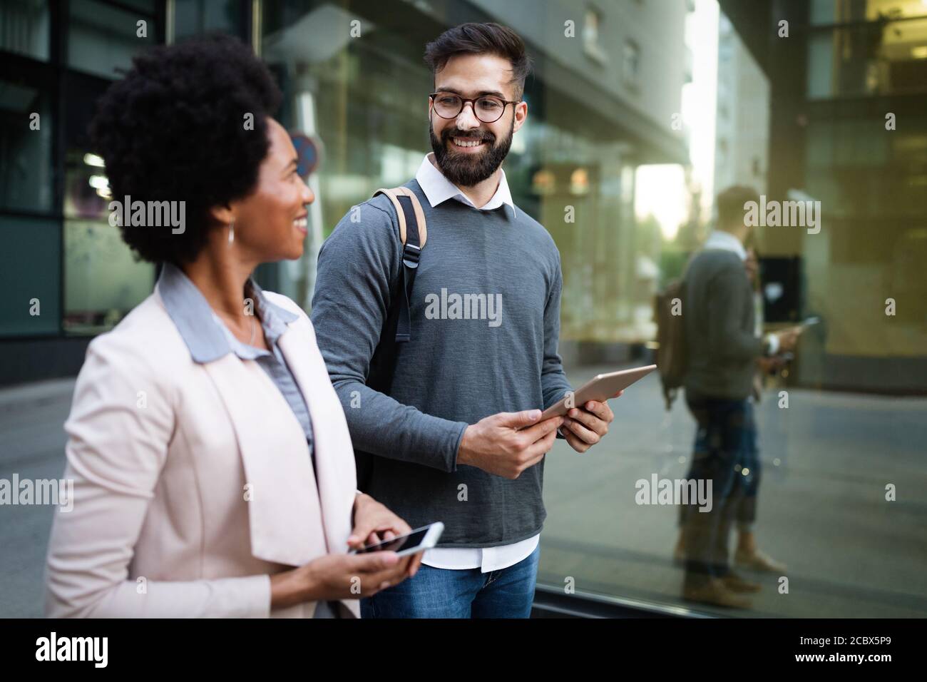 Cheerful people having fun, talking with electronic tablet in city ...